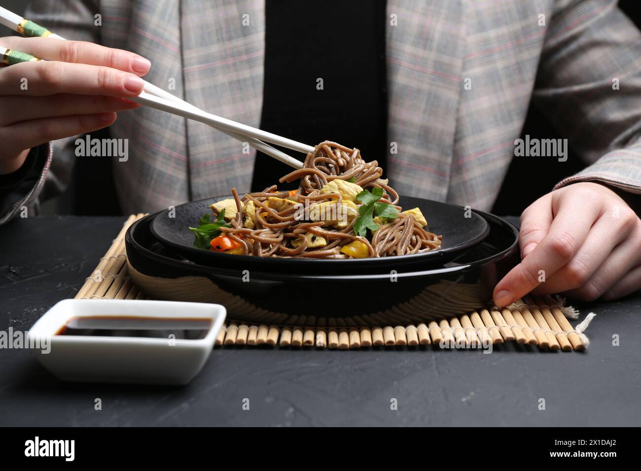 Stir-fry. Woman eating tasty noodles with meat and vegetables at dark ...