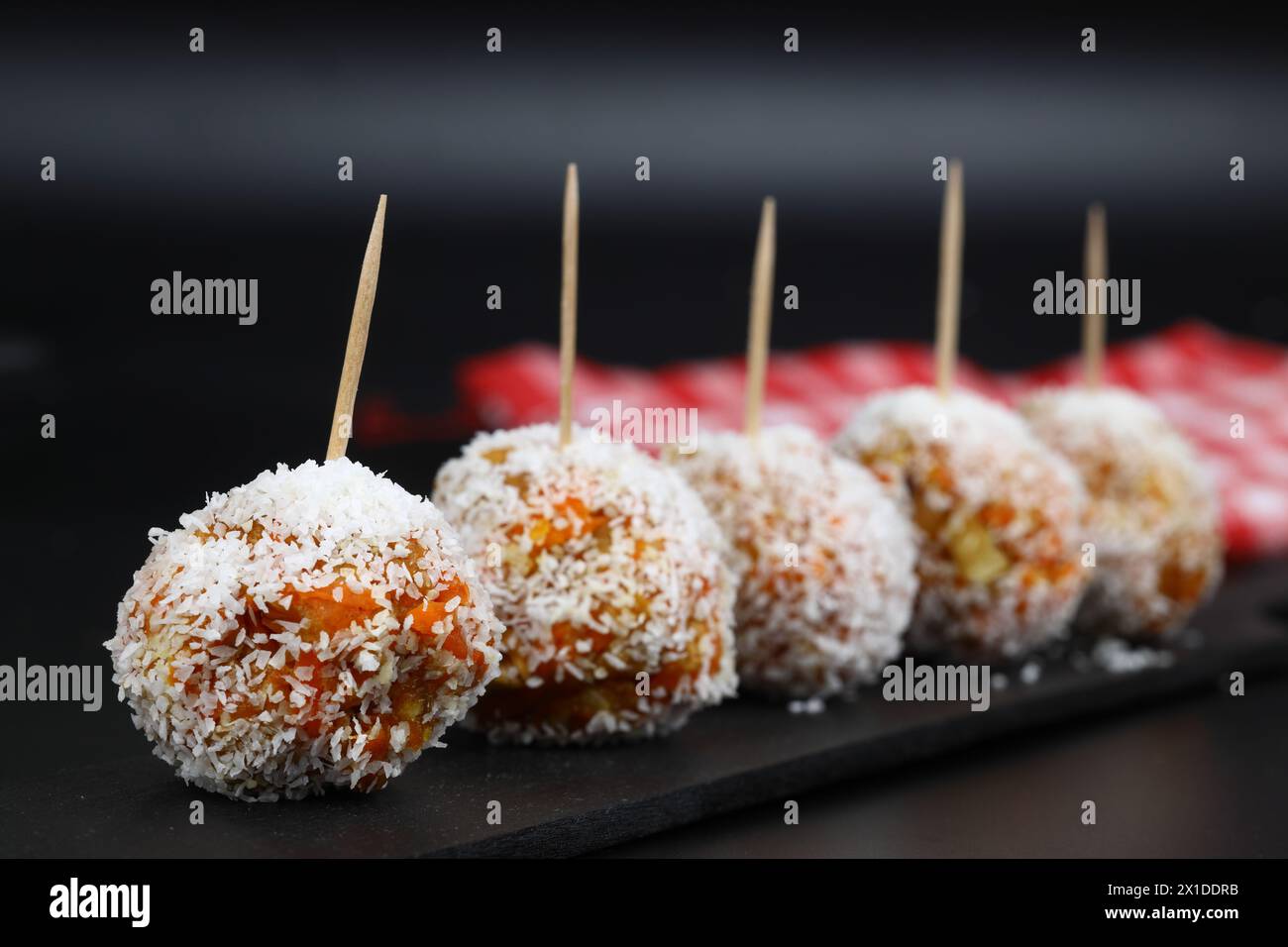 Beautiful sweets with coconut on a black plate on a black background ...