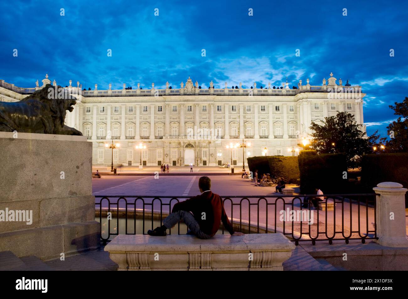 Man sitting on bench looking at the Royal Palace, night view. Oriente ...
