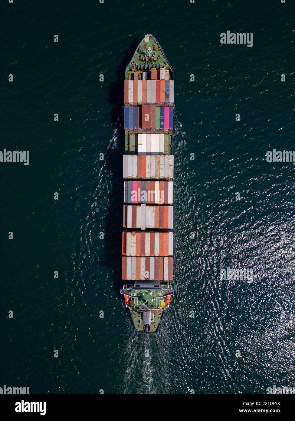 A container ship moves steadily through the ocean, carrying stacked ...