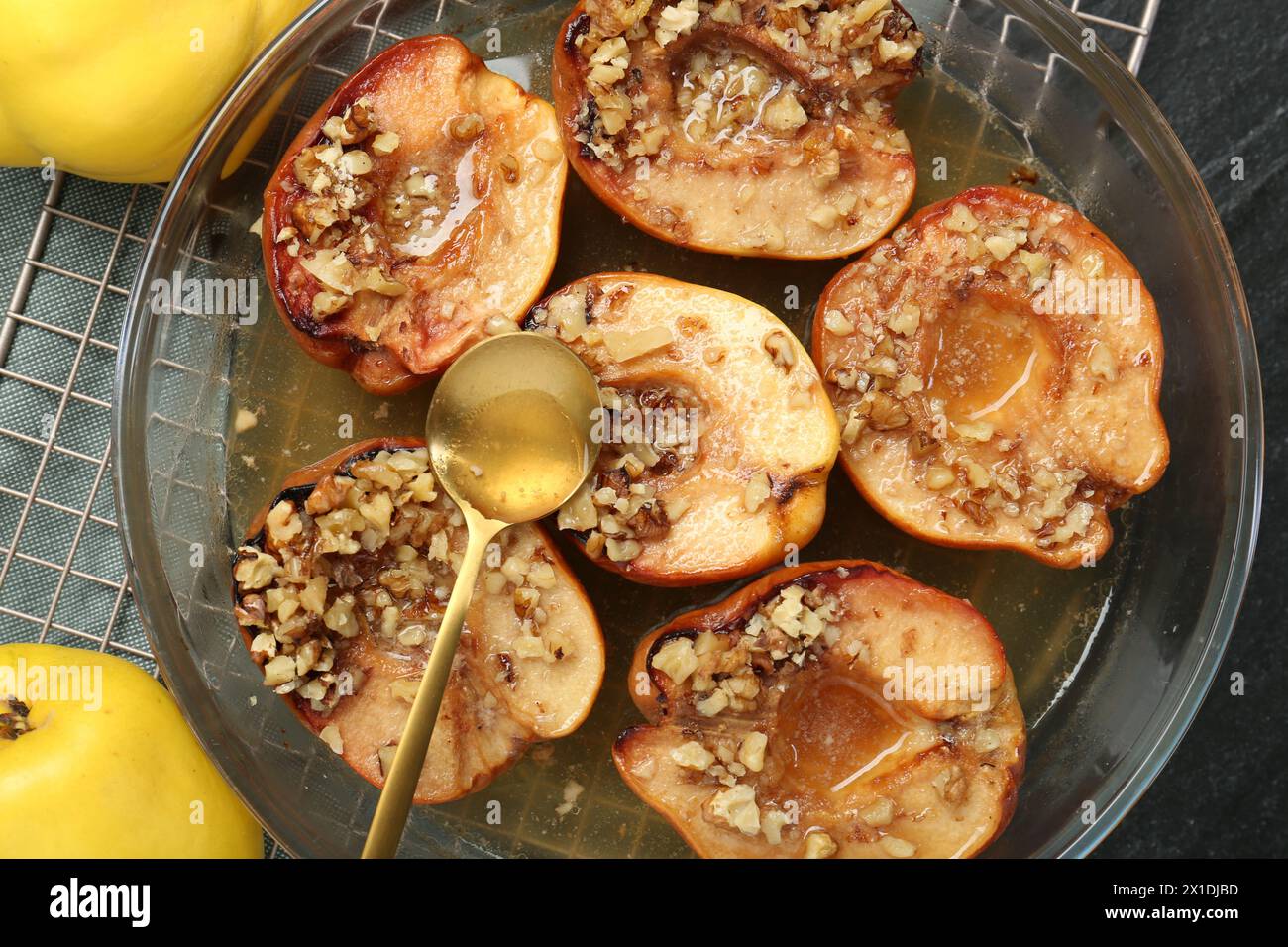 Tasty baked quinces with walnuts and honey in bowl on table, flat lay ...
