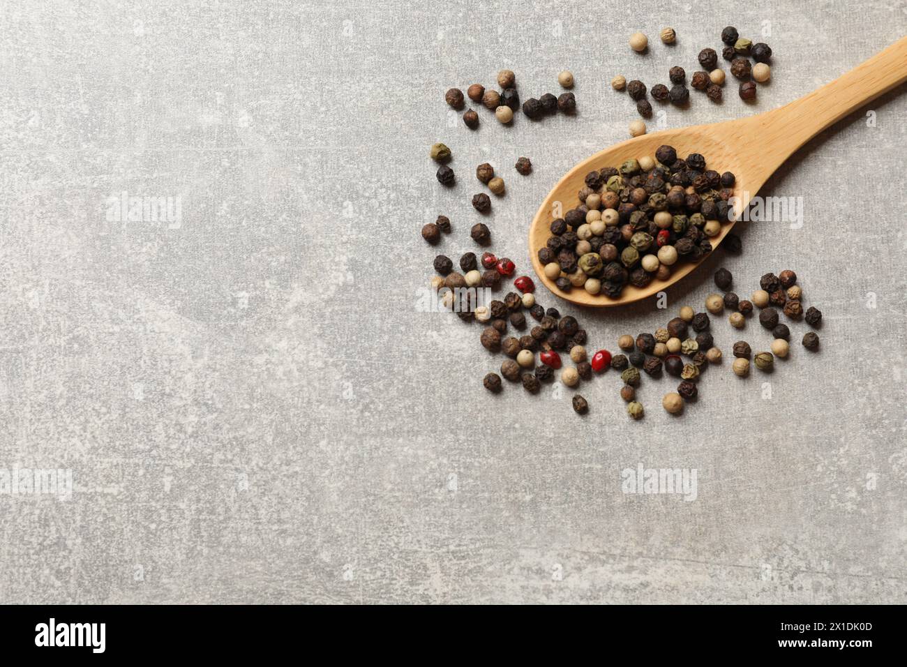 Aromatic spice. Different peppers in spoon on grey table, top view ...