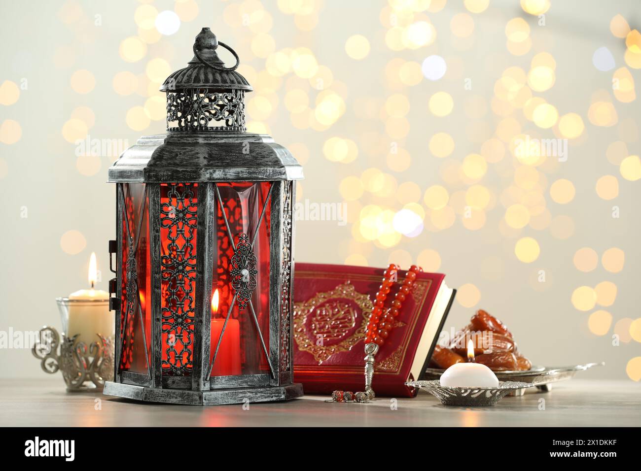 Arabic lantern, Quran, misbaha, candles and dates on table against ...