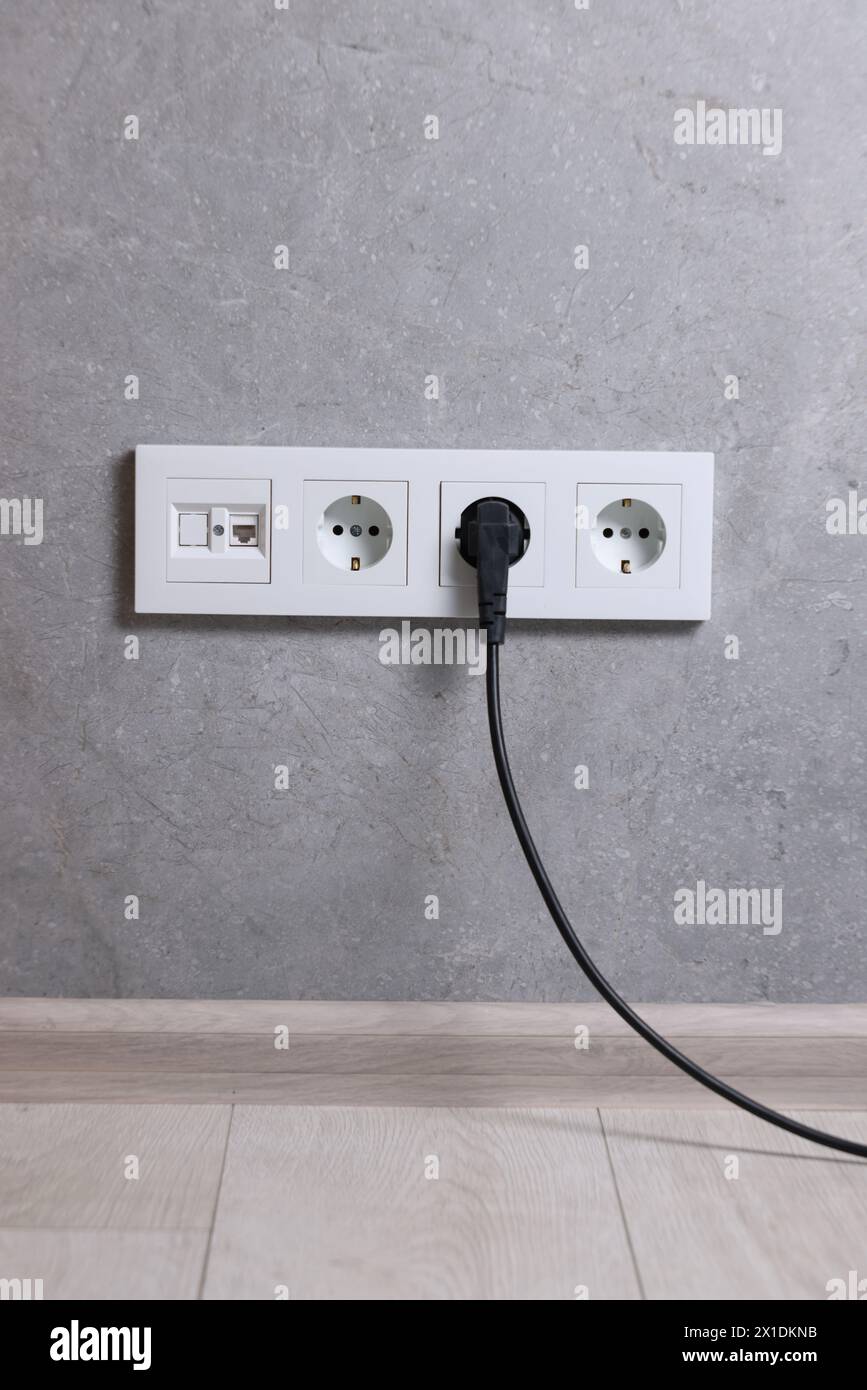 Power sockets and electric plug on grey wall Stock Photo - Alamy