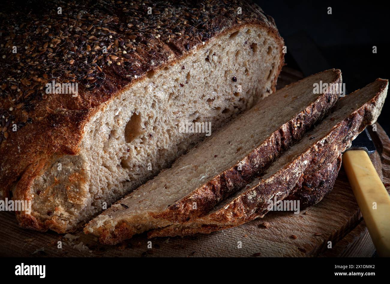 Sliced seeded sourdough loaf closeup on wooden cutting board with ...
