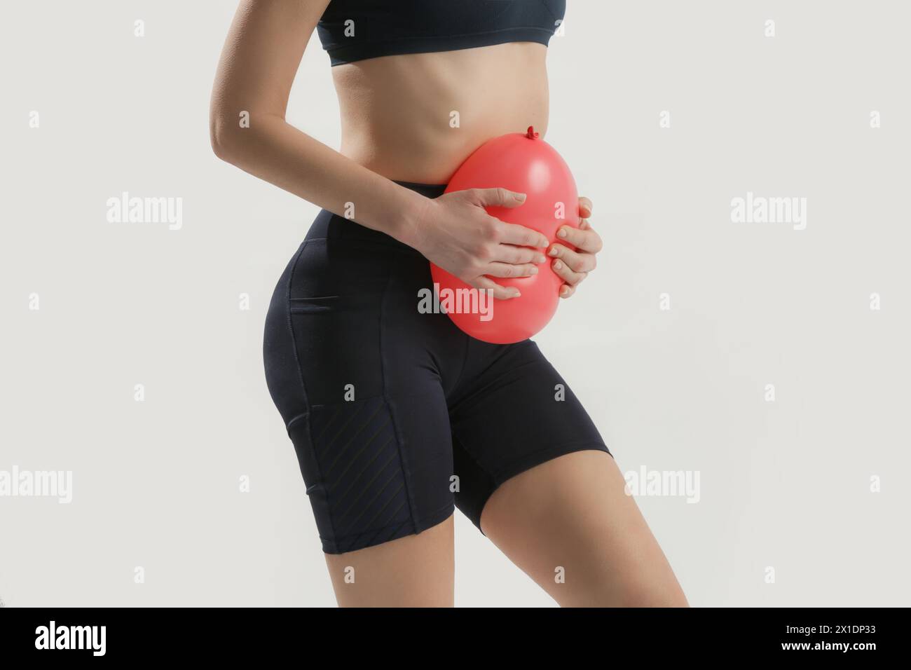 Young woman holding balloon as a sign of an stomach inflation, bloating ...