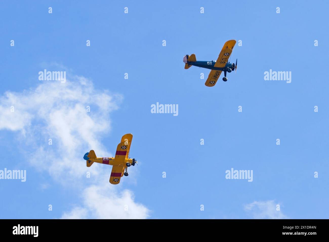 Two old style biplanes flying in formation in the bright sky near ...
