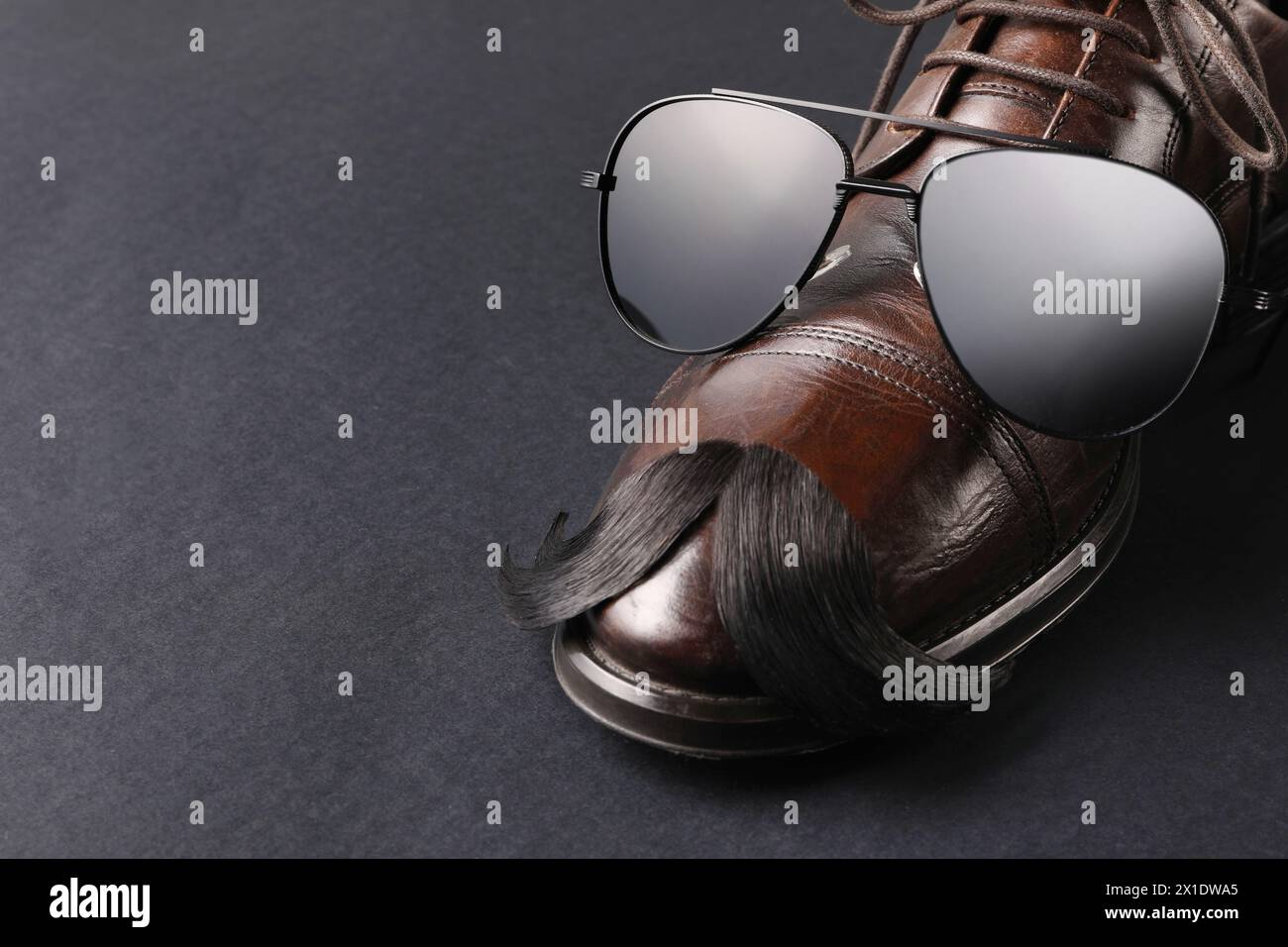 Artificial moustache, shoe and sunglasses on black background, closeup ...