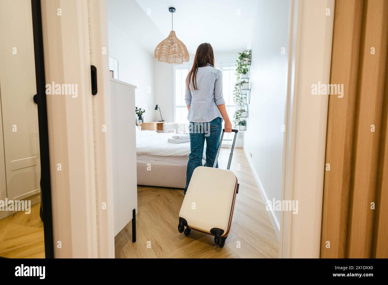 Rear view of a young woman entering a hotel room with her luggage Stock ...