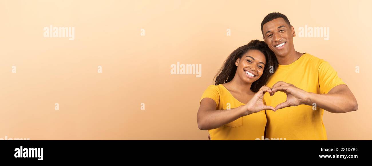 Couple forming heart shape with hands on beige Stock Photo - Alamy