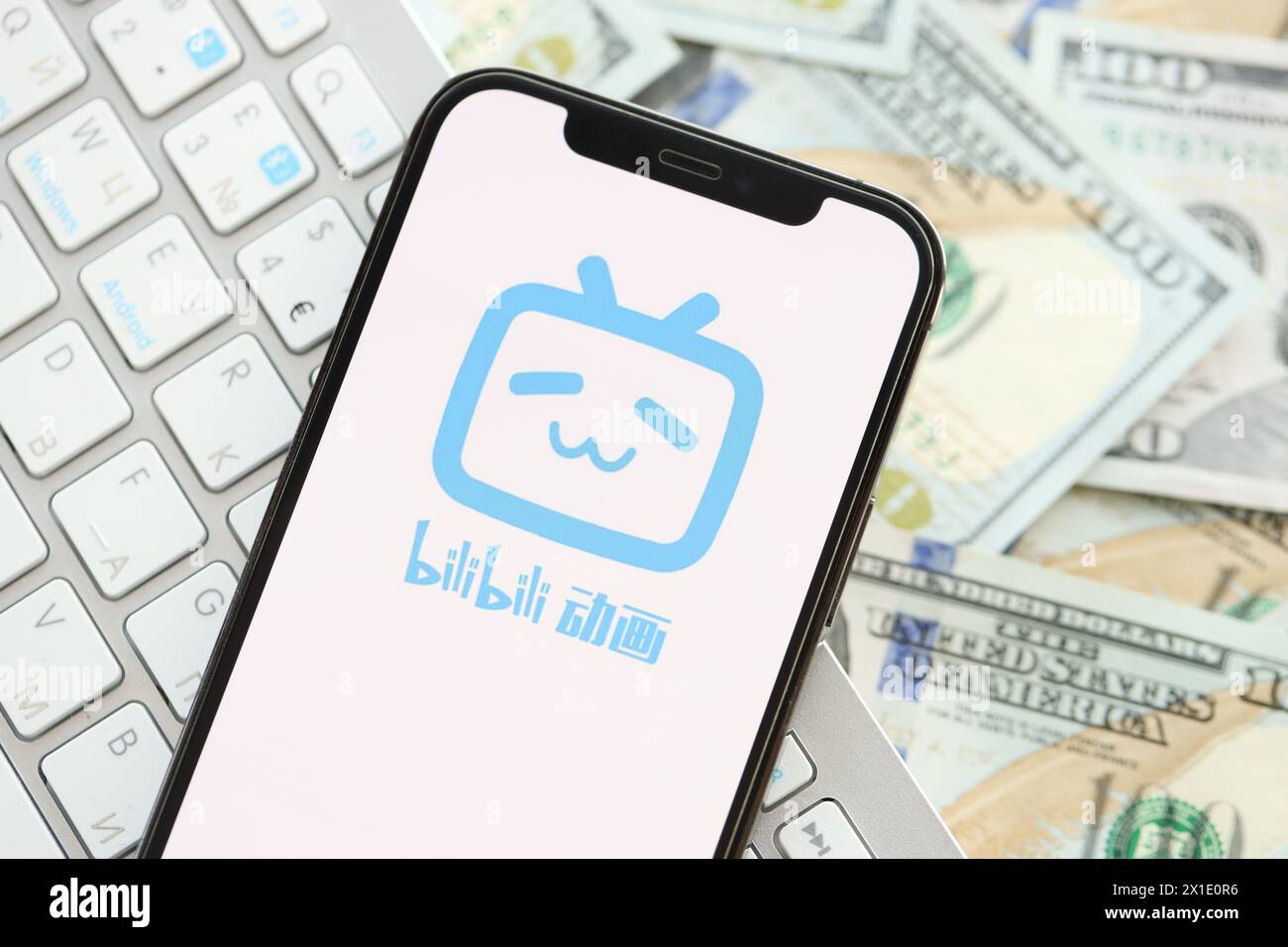 KYIV, UKRAINE - APRIL 1, 2024 Bilibili icon on smartphone screen on many usd money bills. iPhone ...