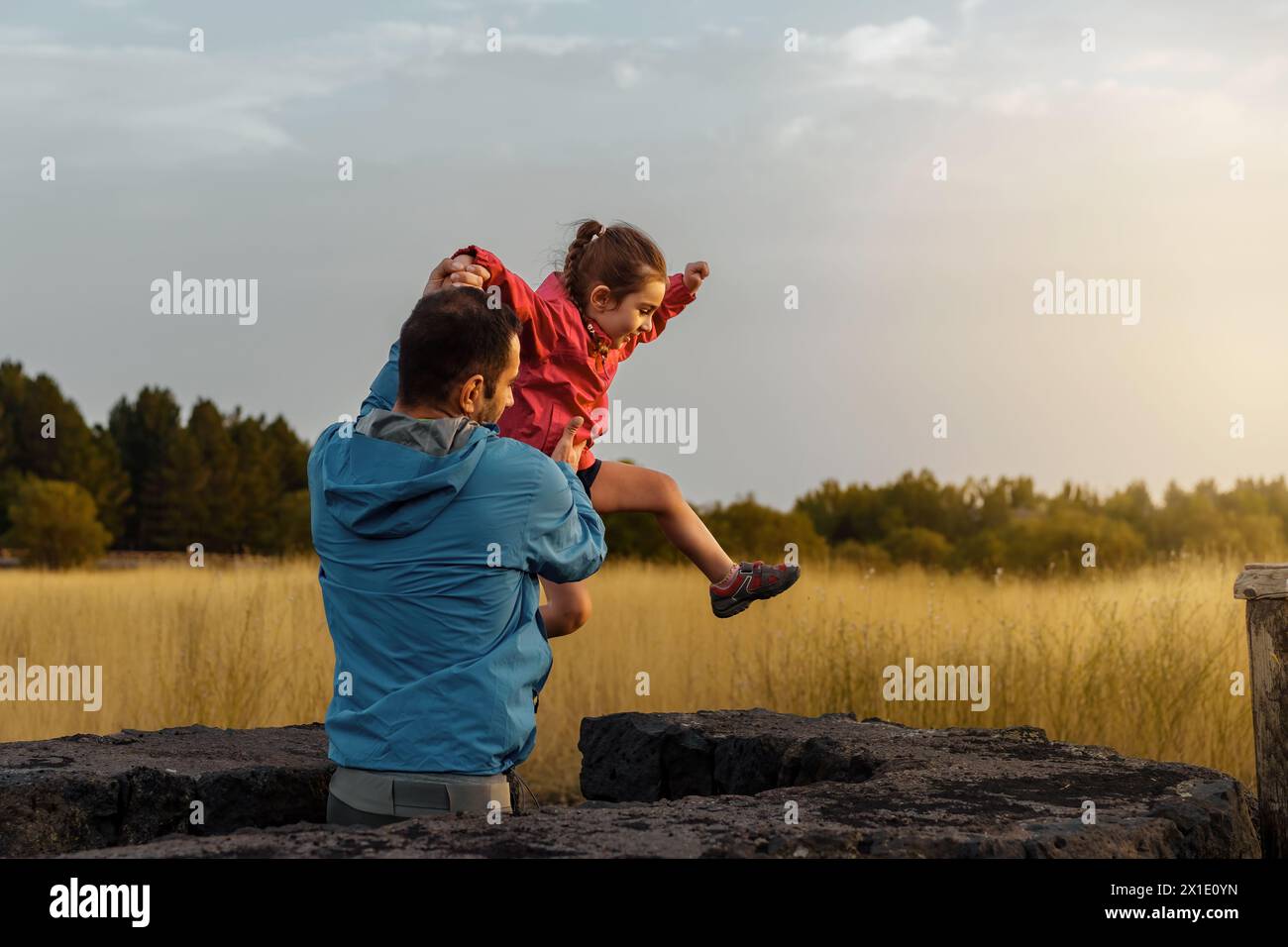 Family fun outdoor - child leaps from a stone wall into father's arms ...
