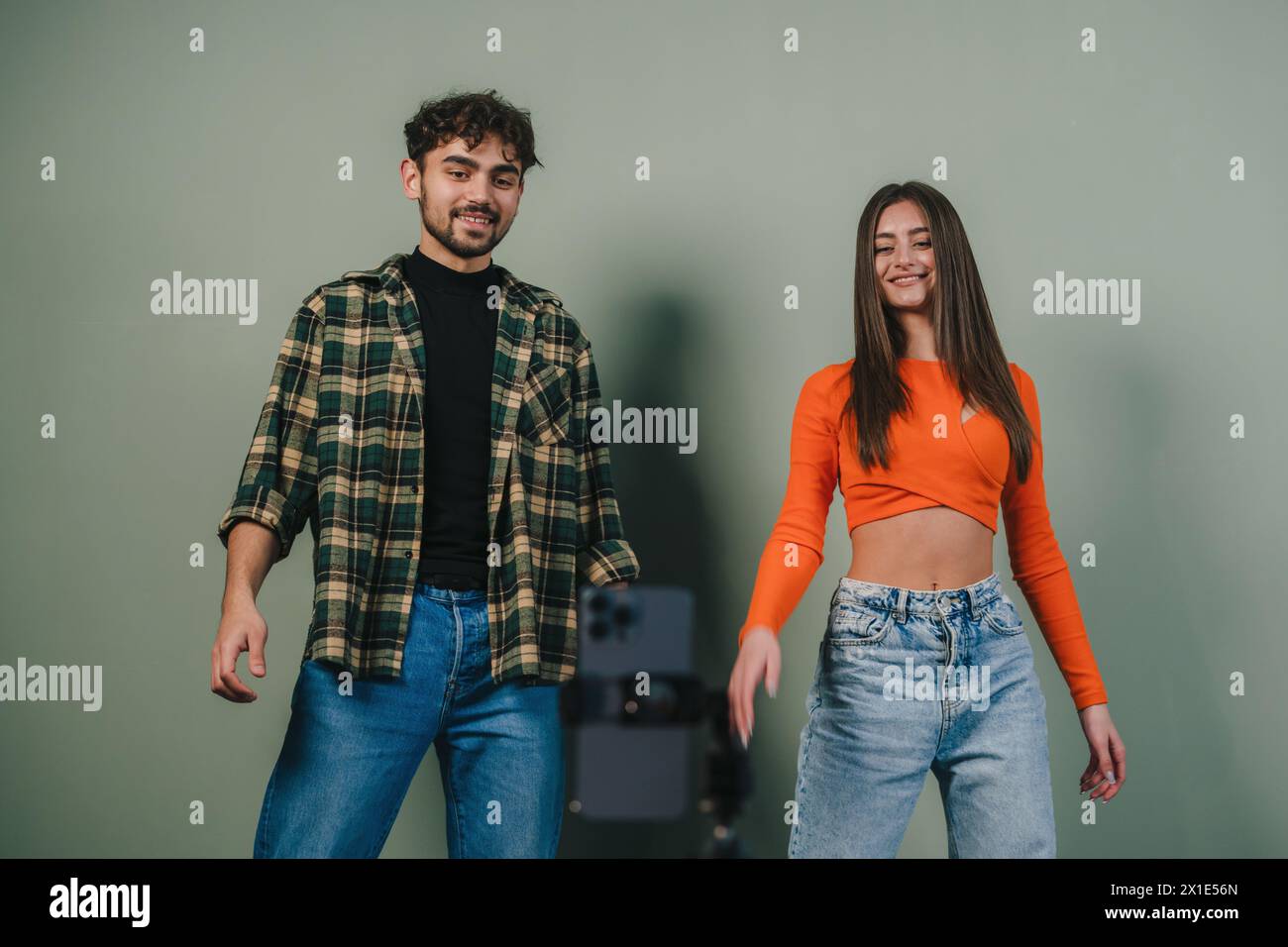 Cheerful woman and man having fun, moving to music at home recording ...