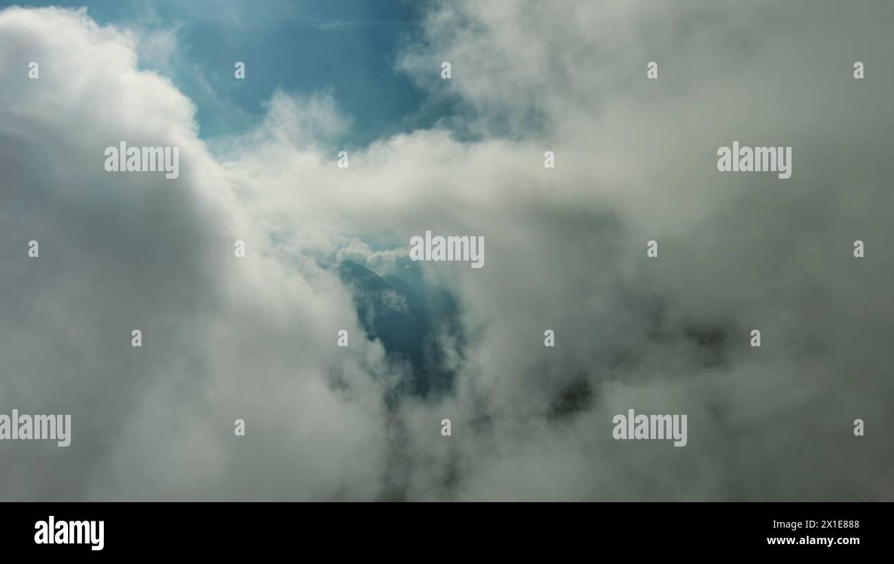 Flying through clouds between mountains Stock Photo - Alamy