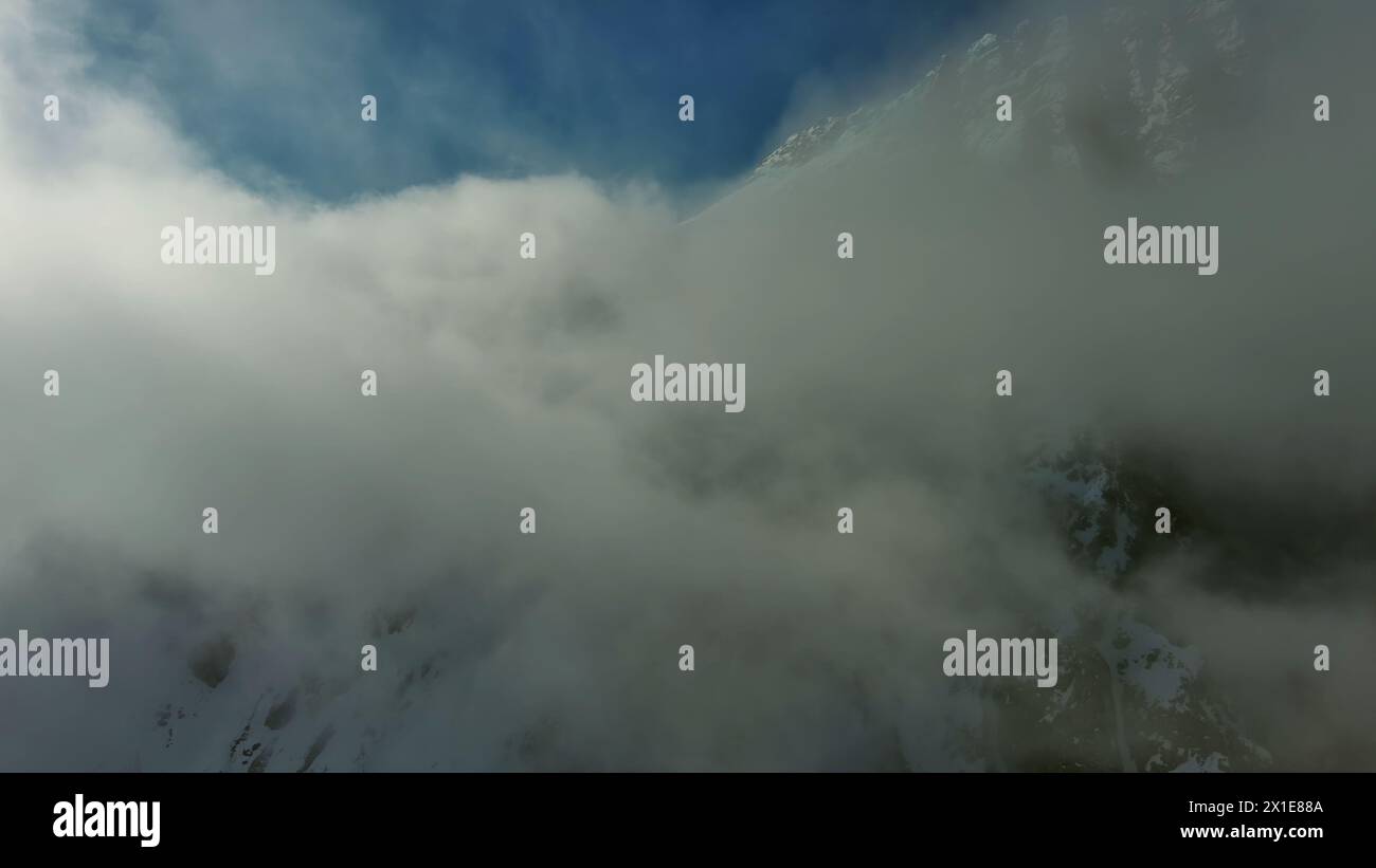 Flying through clouds between mountains Stock Photo - Alamy