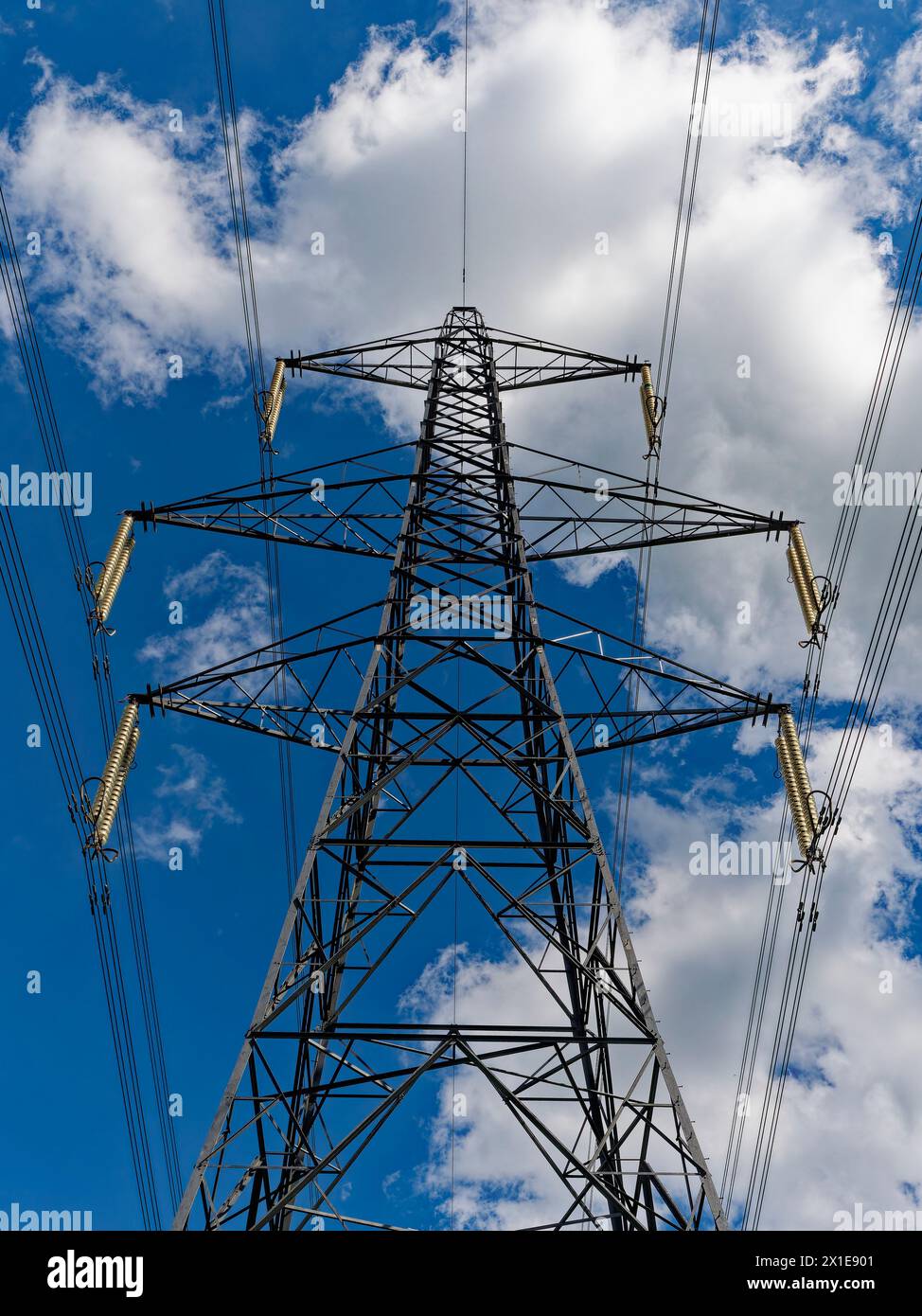 Electricity pylon against partly cloudy sky with wires overhead ...