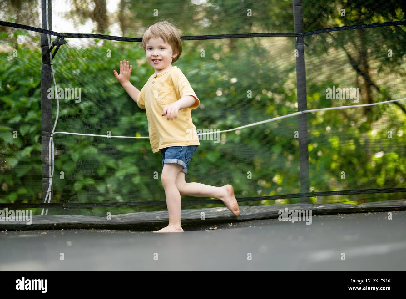 Cute little boy jumping on a trampoline in a backyard on warm and sunny ...