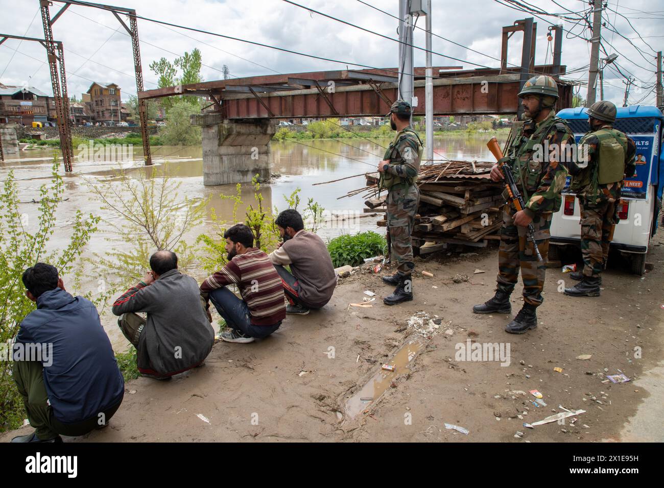 Indian army soldiers stand on guard as People gather along the bank of ...