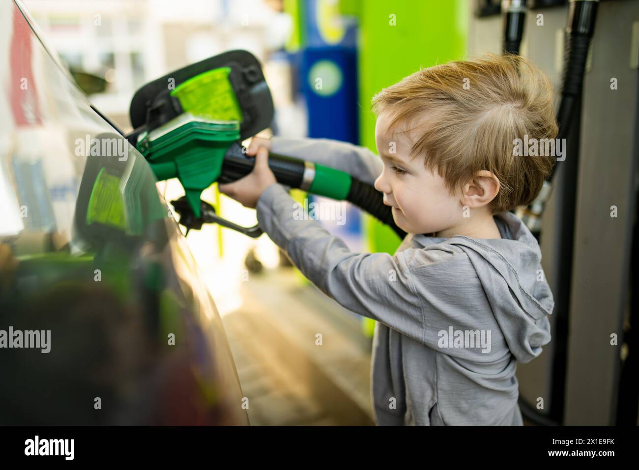 Cute little blond boy holding pump nozzle. Small funny kid helping ...