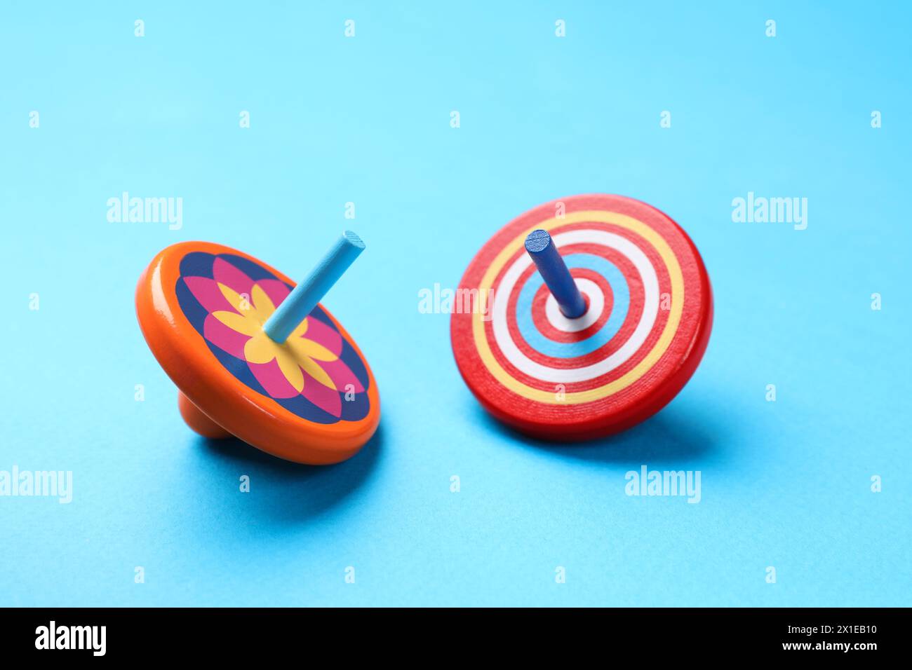 Two colorful spinning tops on light blue background Stock Photo - Alamy