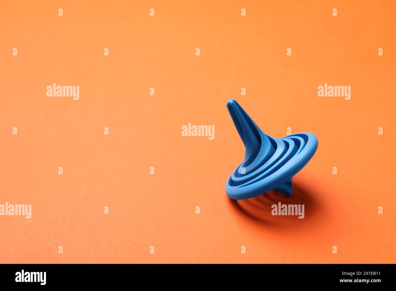 One blue spinning top on orange background Stock Photo - Alamy