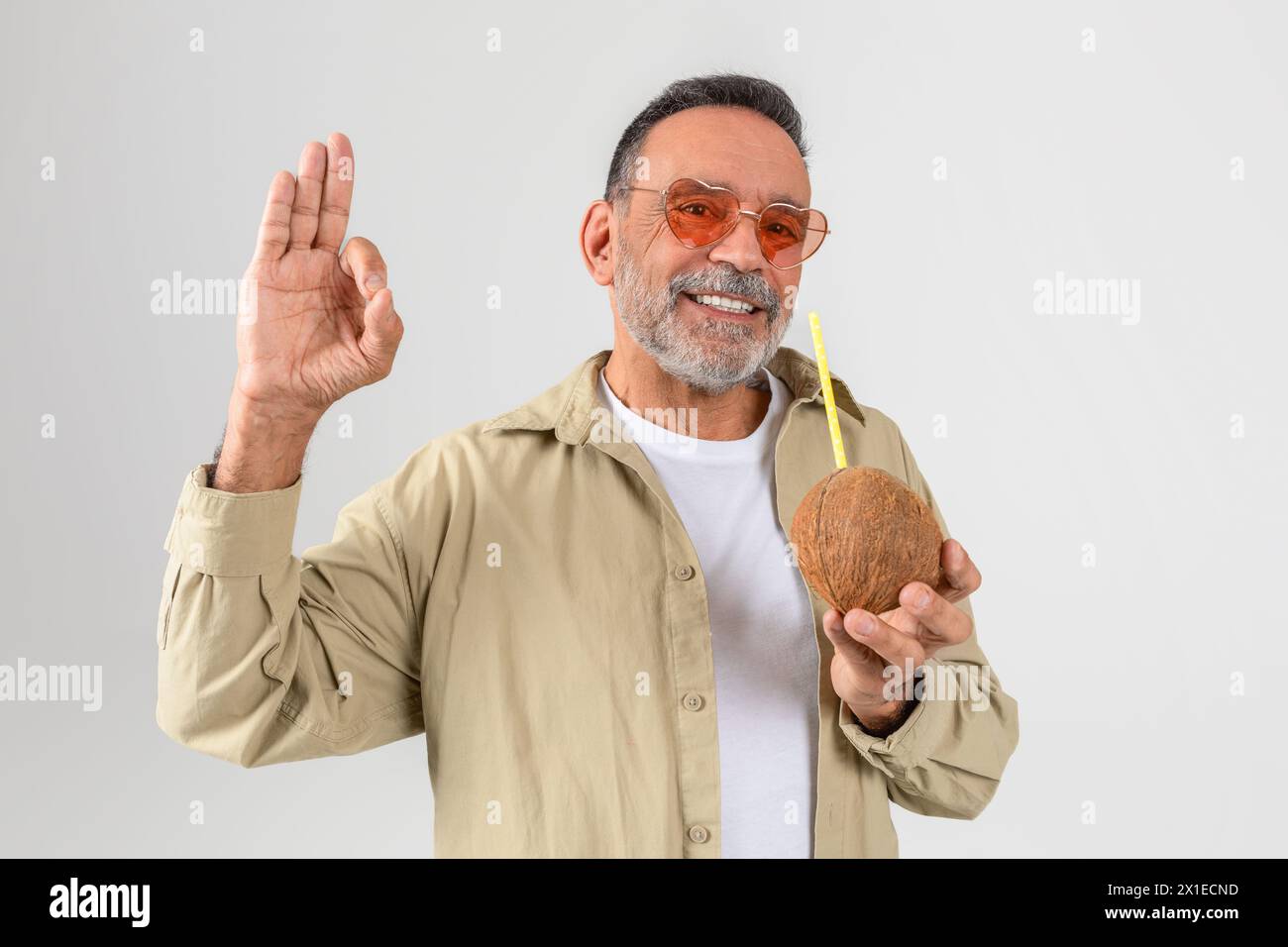 Senior man waving hand and holding coconut Stock Photo - Alamy