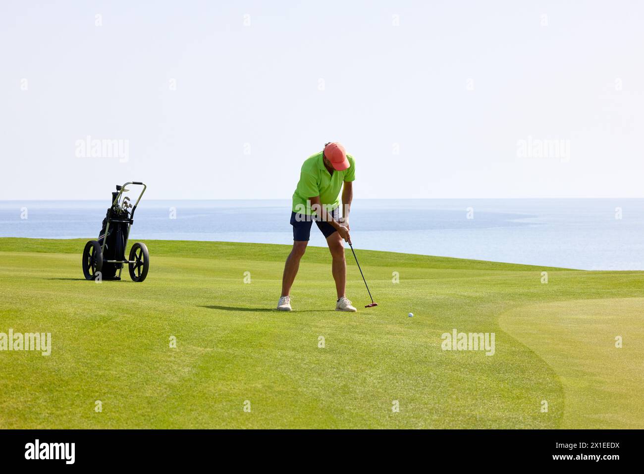 Golfer on the putting green with golf iron, early in the morning during ...