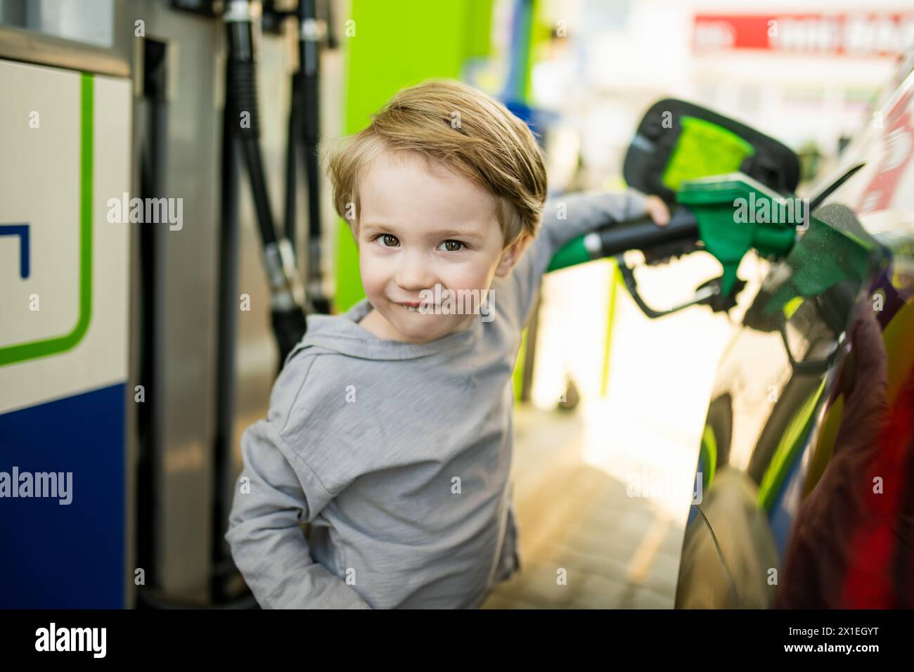 Cute little blond boy holding pump nozzle. Small funny kid helping ...