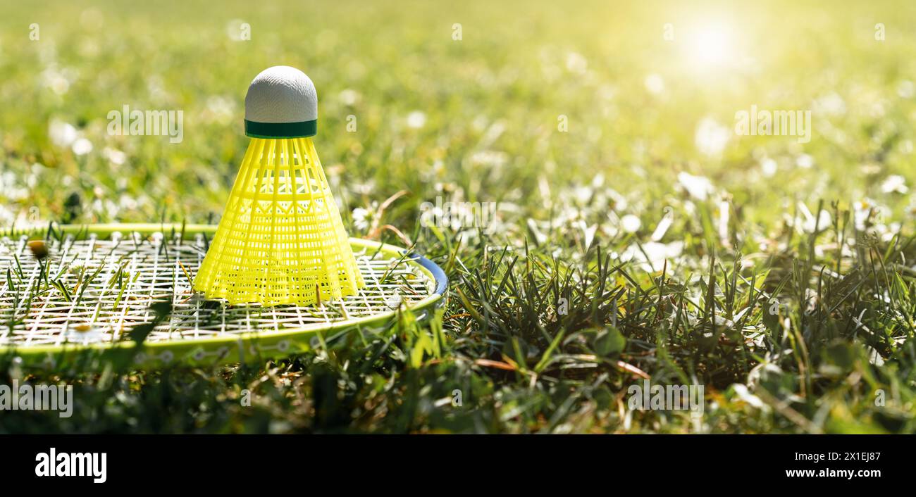 Yellow shuttlecock and badminton racket on the green grass of lawn ...