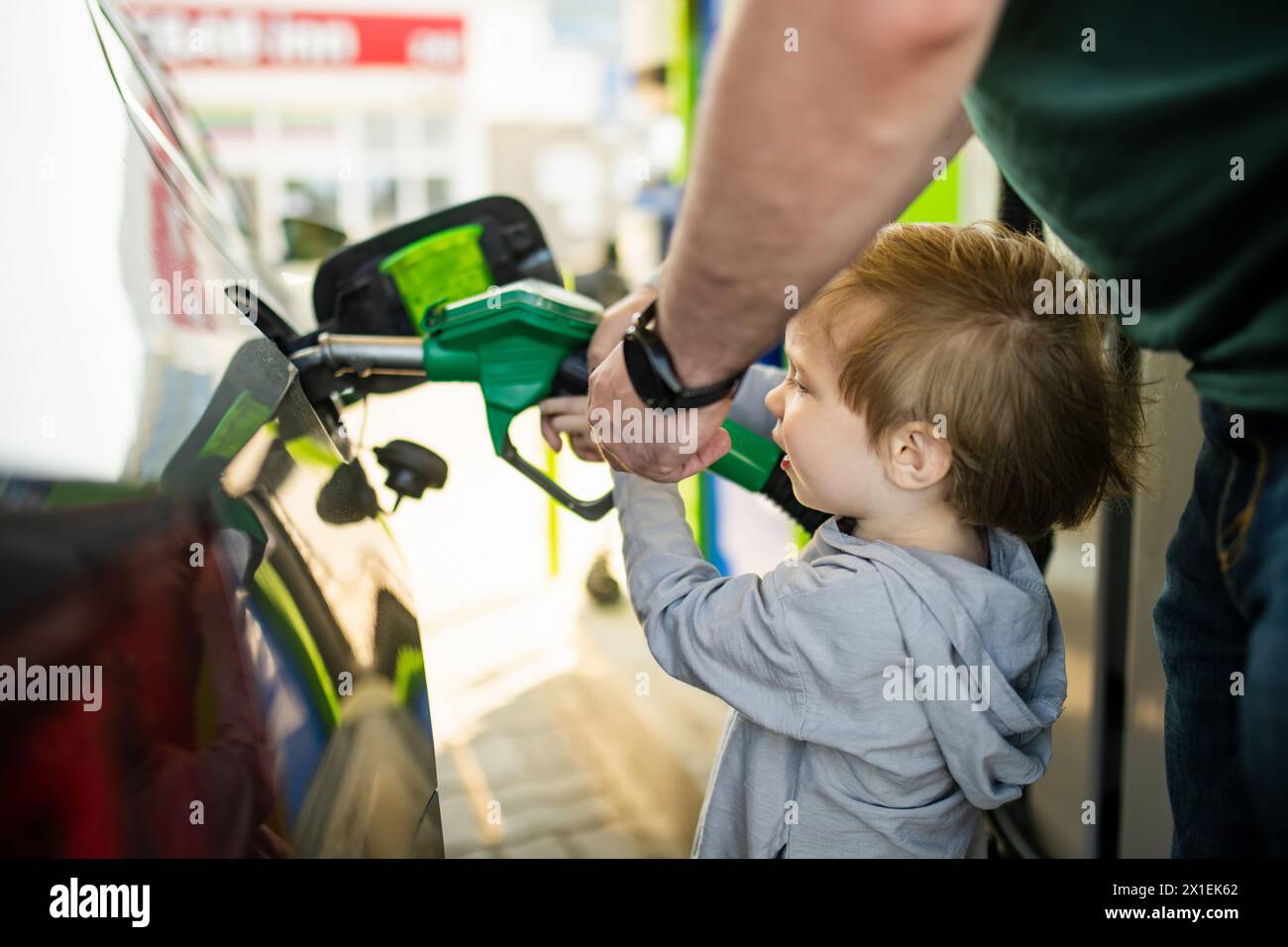 Cute little blond boy holding pump nozzle. Small funny kid helping ...