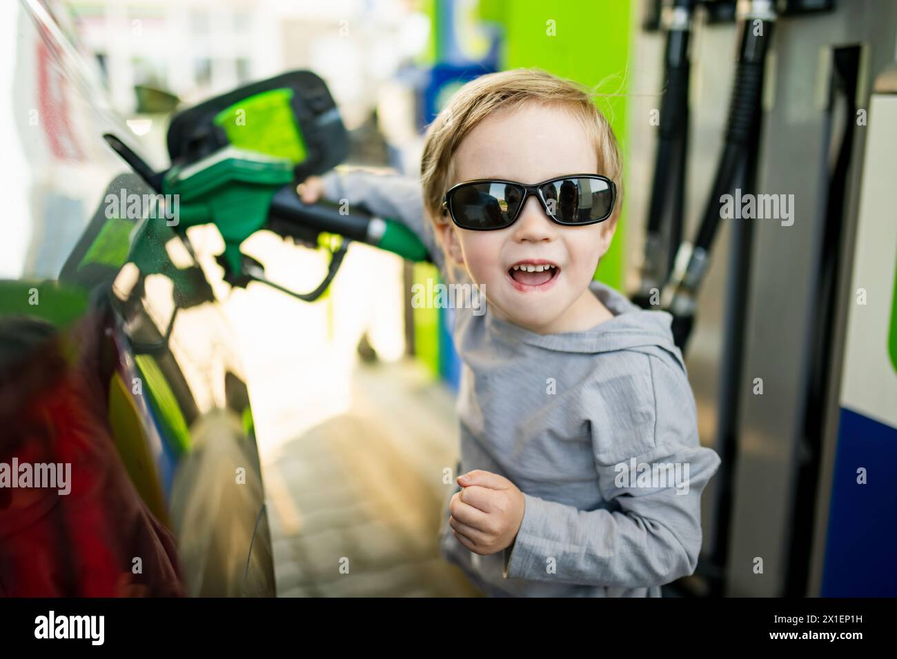 Cute little blond boy holding pump nozzle. Small funny kid helping ...