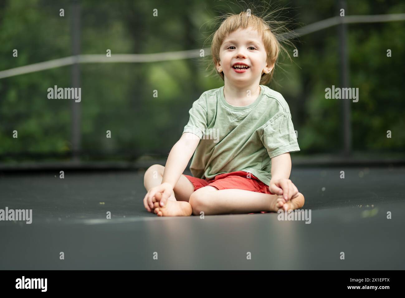 Cute little boy jumping on a trampoline in a backyard on warm and sunny ...