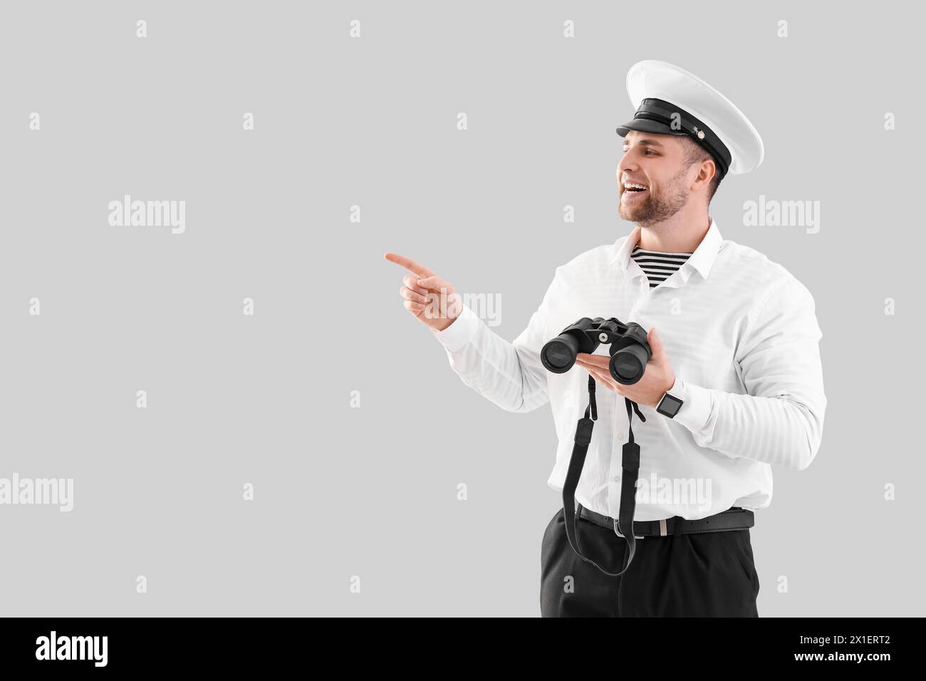 Young male sailor with binoculars pointing at something on white ...