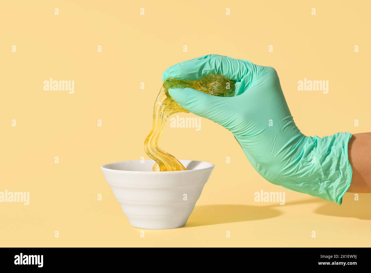 Beautician hand with sugaring paste on pale yellow background Stock ...