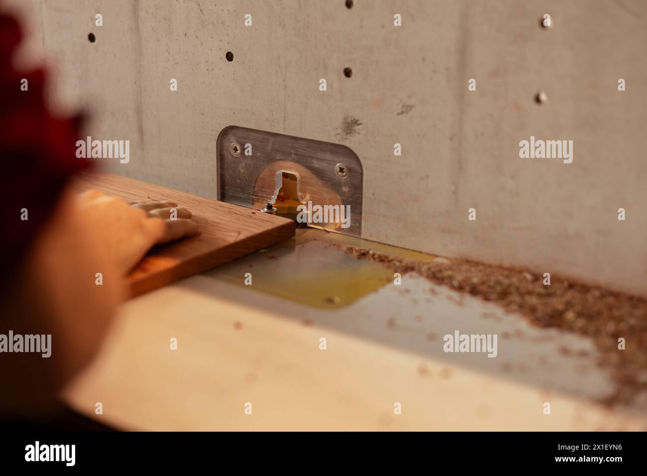Man at workbench putting lumber block though spindle moulder, doing ...