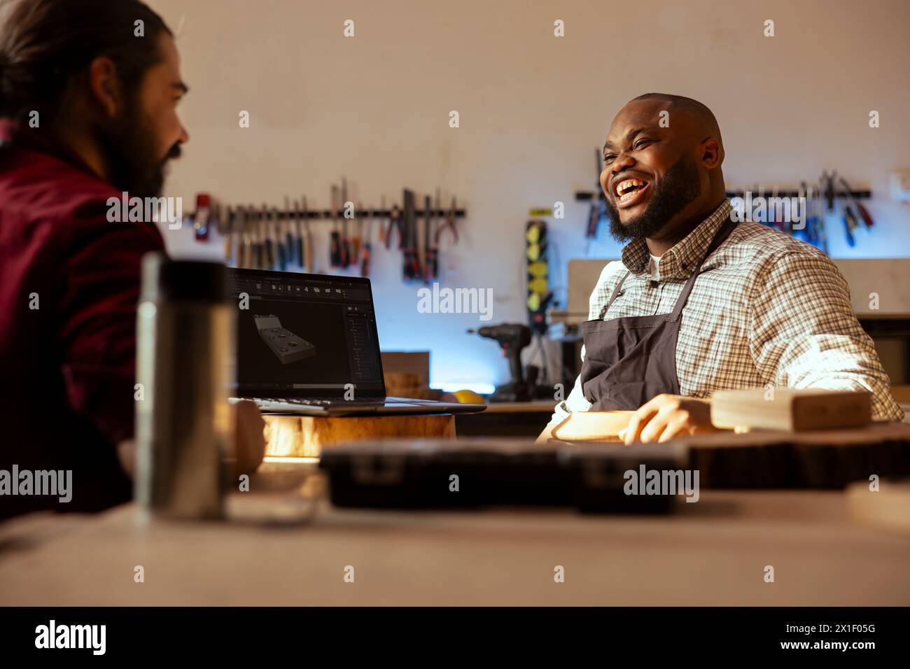Happy carpenter looking over blueprints schematics on laptop in CAD ...