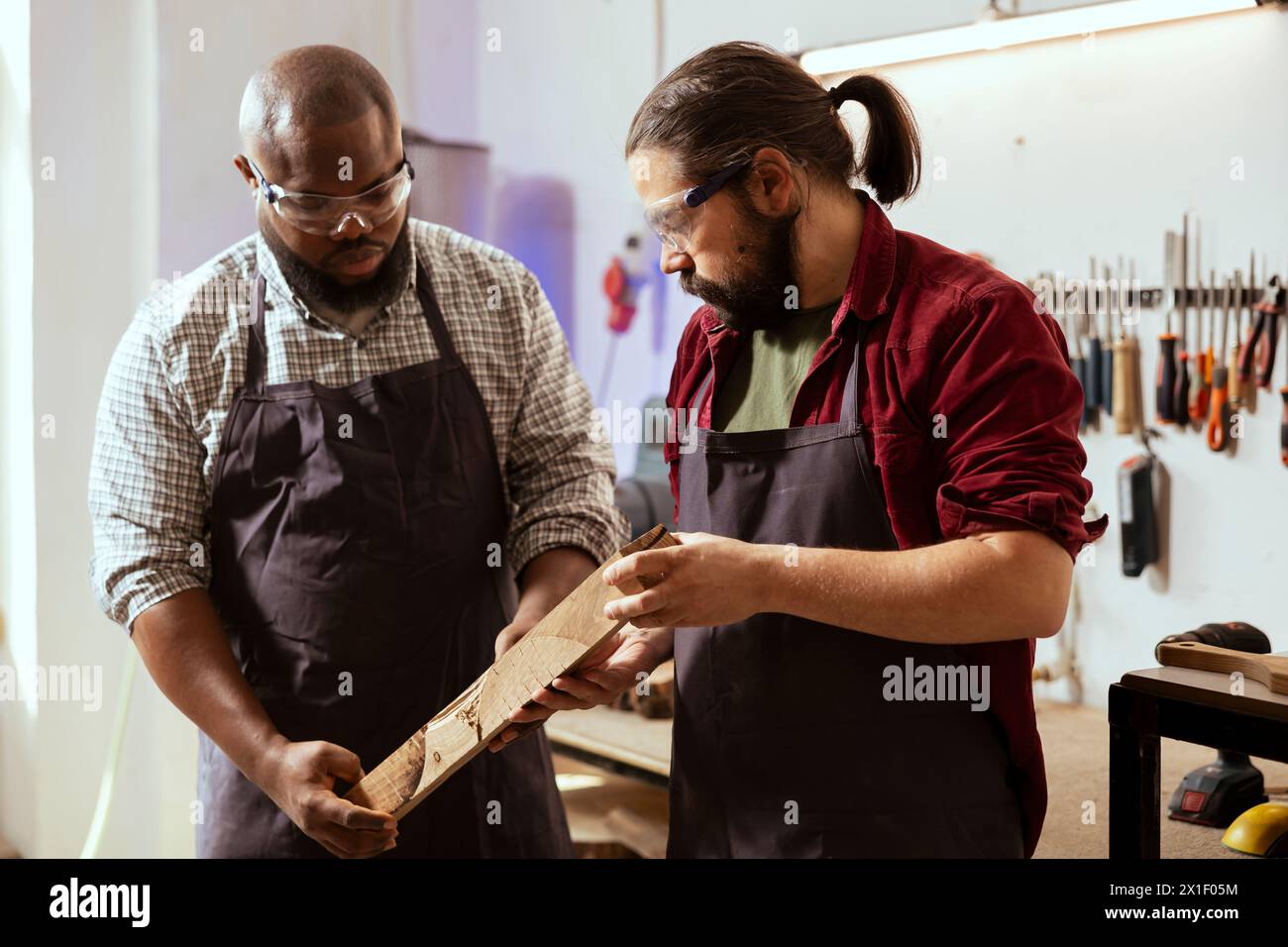 Woodworker holding timber block, brainstorming with colleague next ...