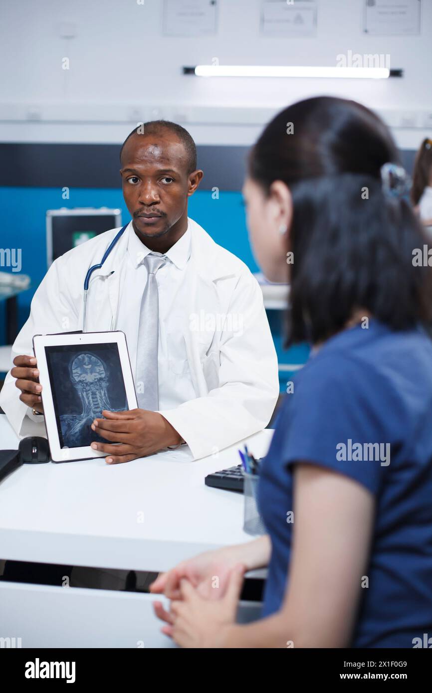 African American doctor uses a tablet to diagnose cervical vertebra ...