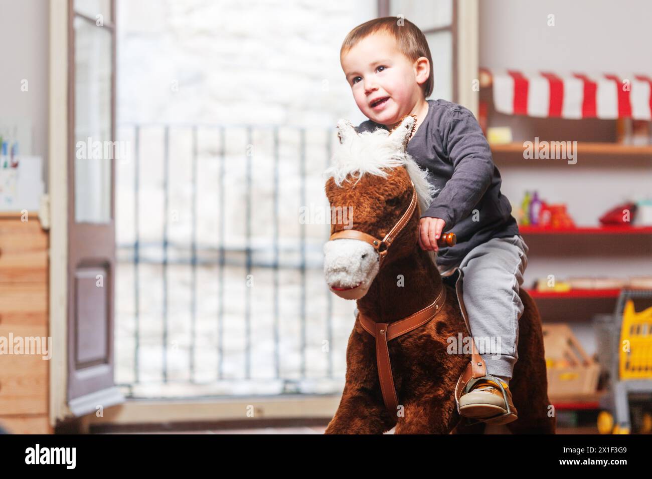 Toddler riding on his rocking horse while playing in the playroom at ...