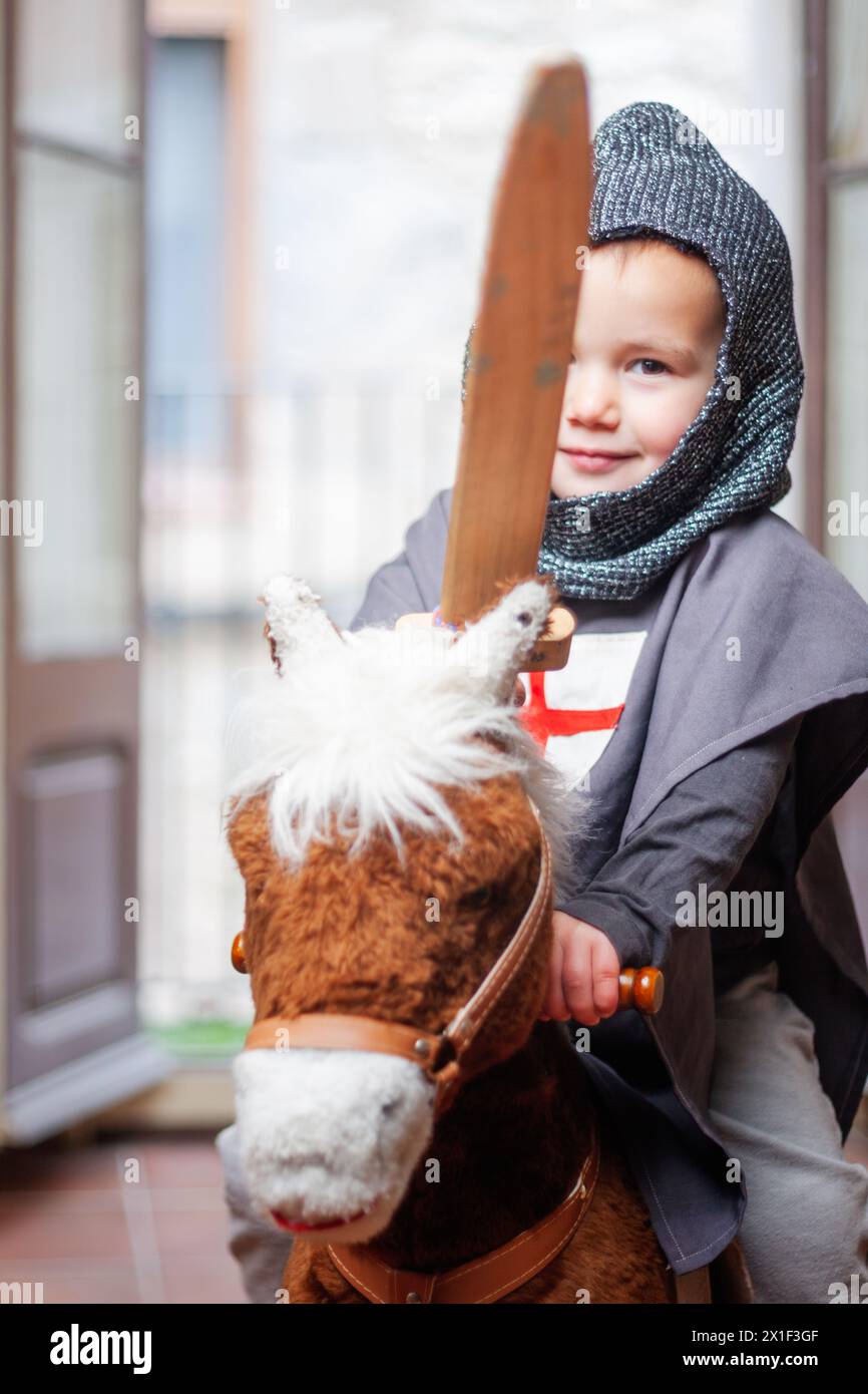 Boy dressed as a knight riding his rocking horse and showing off his ...