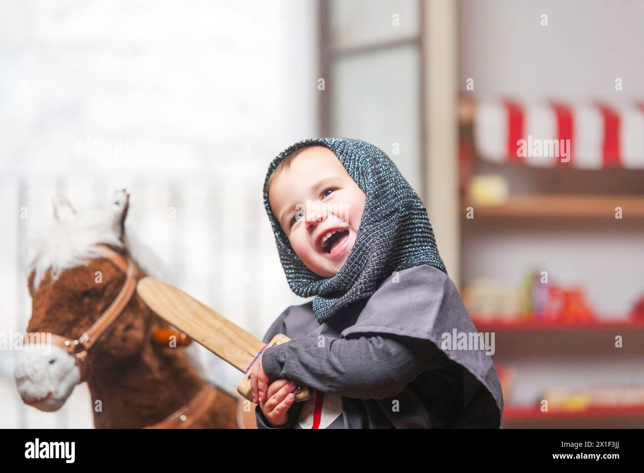 Little boy with a big smile plays knights with his wooden sword in the ...