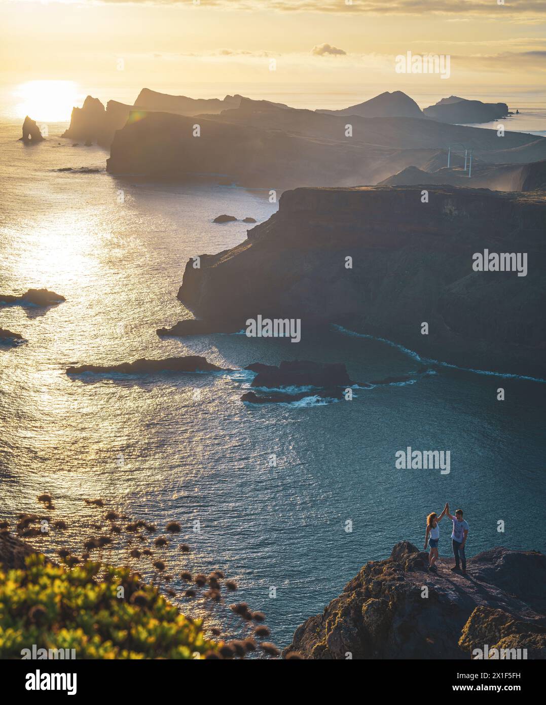 Description: Tourist pair slaps hands at sunrise from a vantage point ...