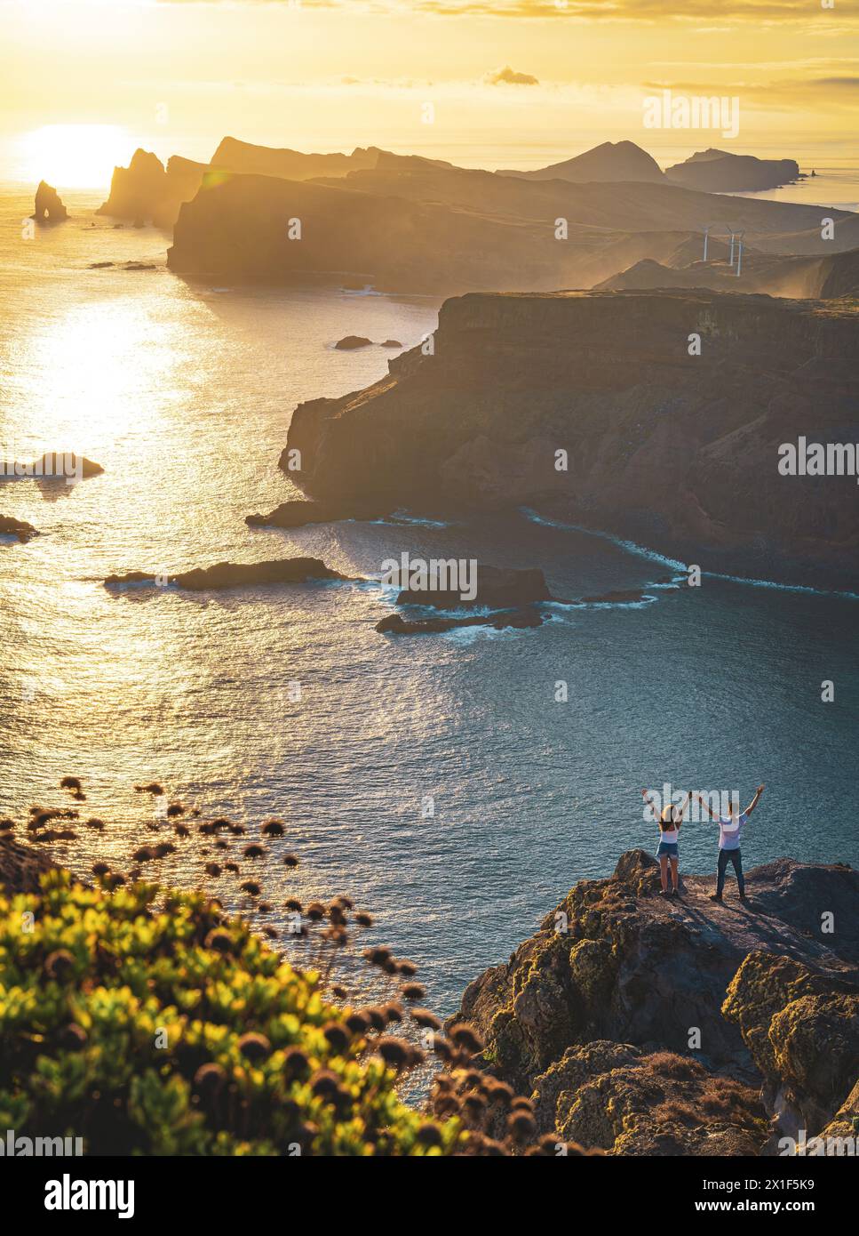 Description: Happy tourist pair raises their arms in the air at sunrise ...