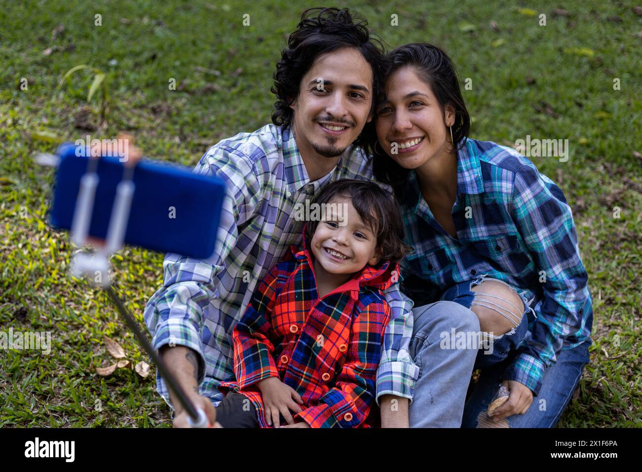 Latin American parents smile with their 3-year-old son while taking a ...