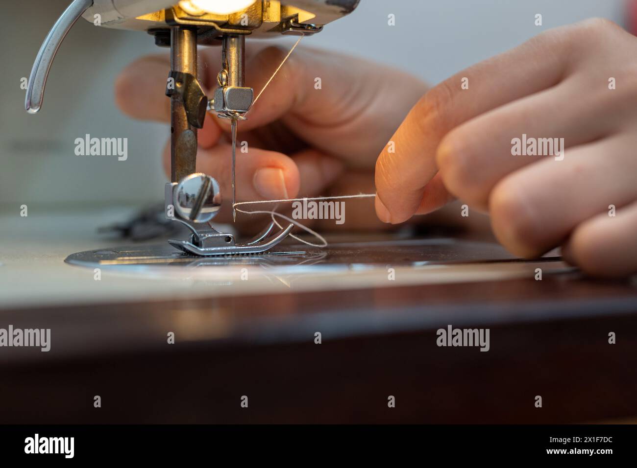 Latin American seamstress inserts thread into sewing machine needle ...