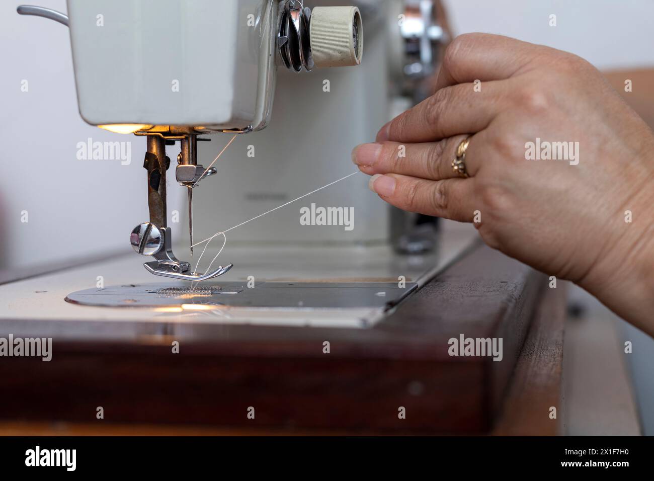 Latin American seamstress inserts thread into sewing machine needle ...