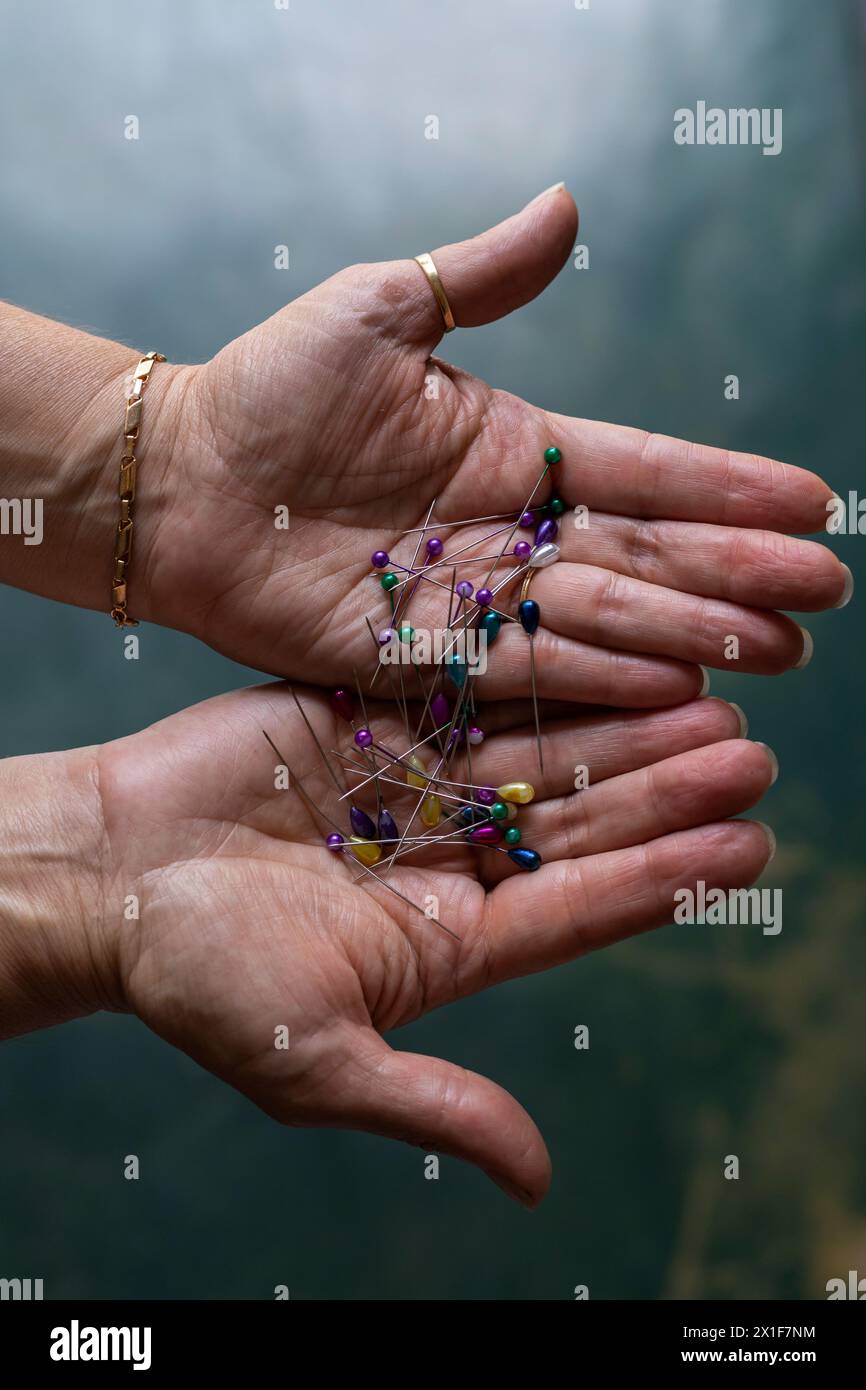 Latin American seamstress hands holding different pins in her palms ...