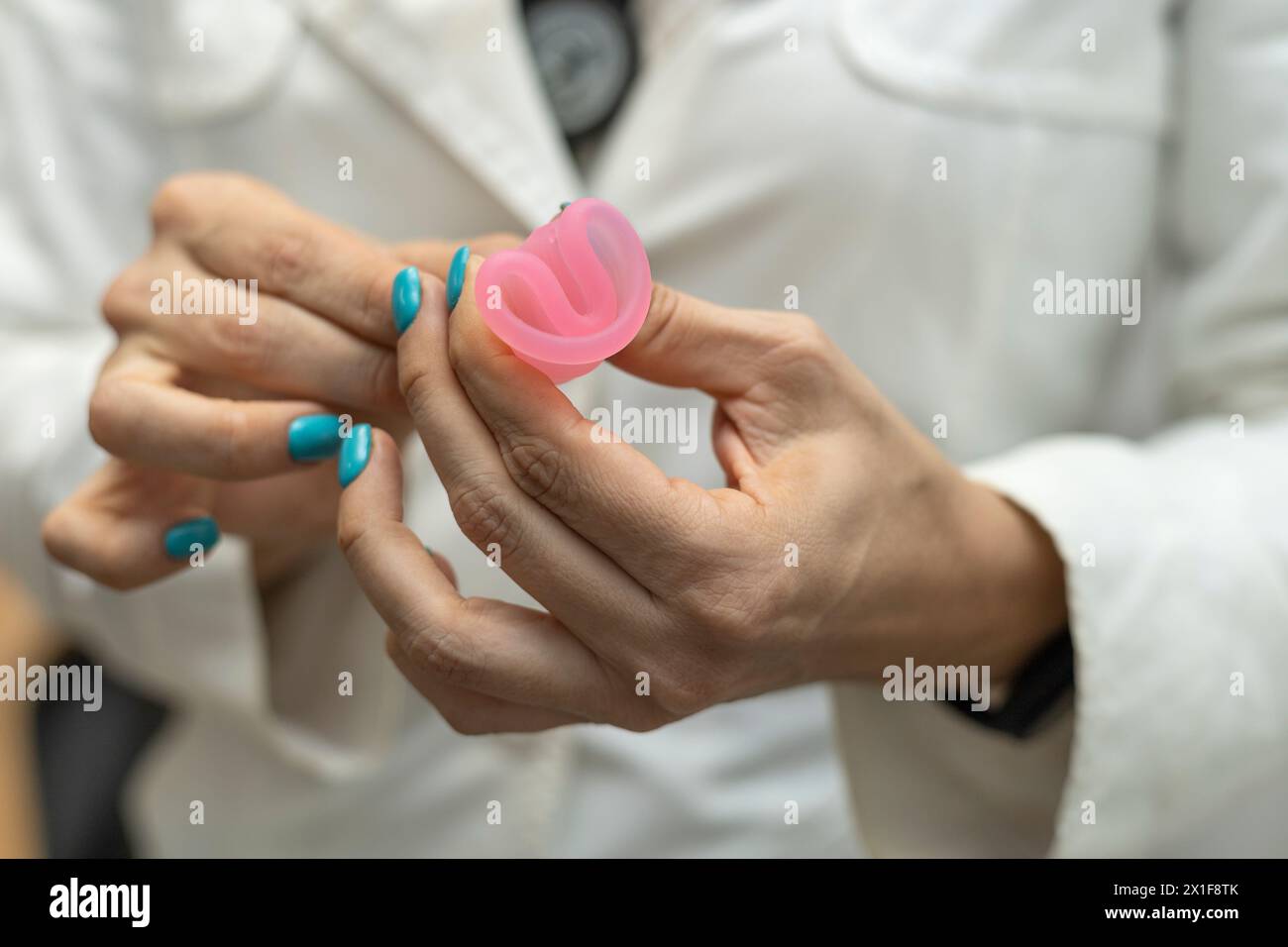 Doctor's hand holds menstrual cup and shows the correct way to insert ...