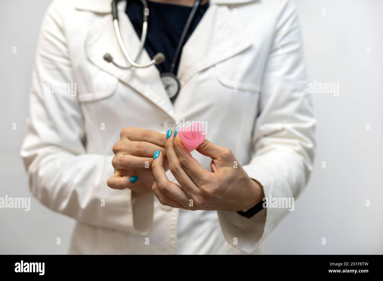 Doctor's hand holds menstrual cup and shows the correct way to insert ...