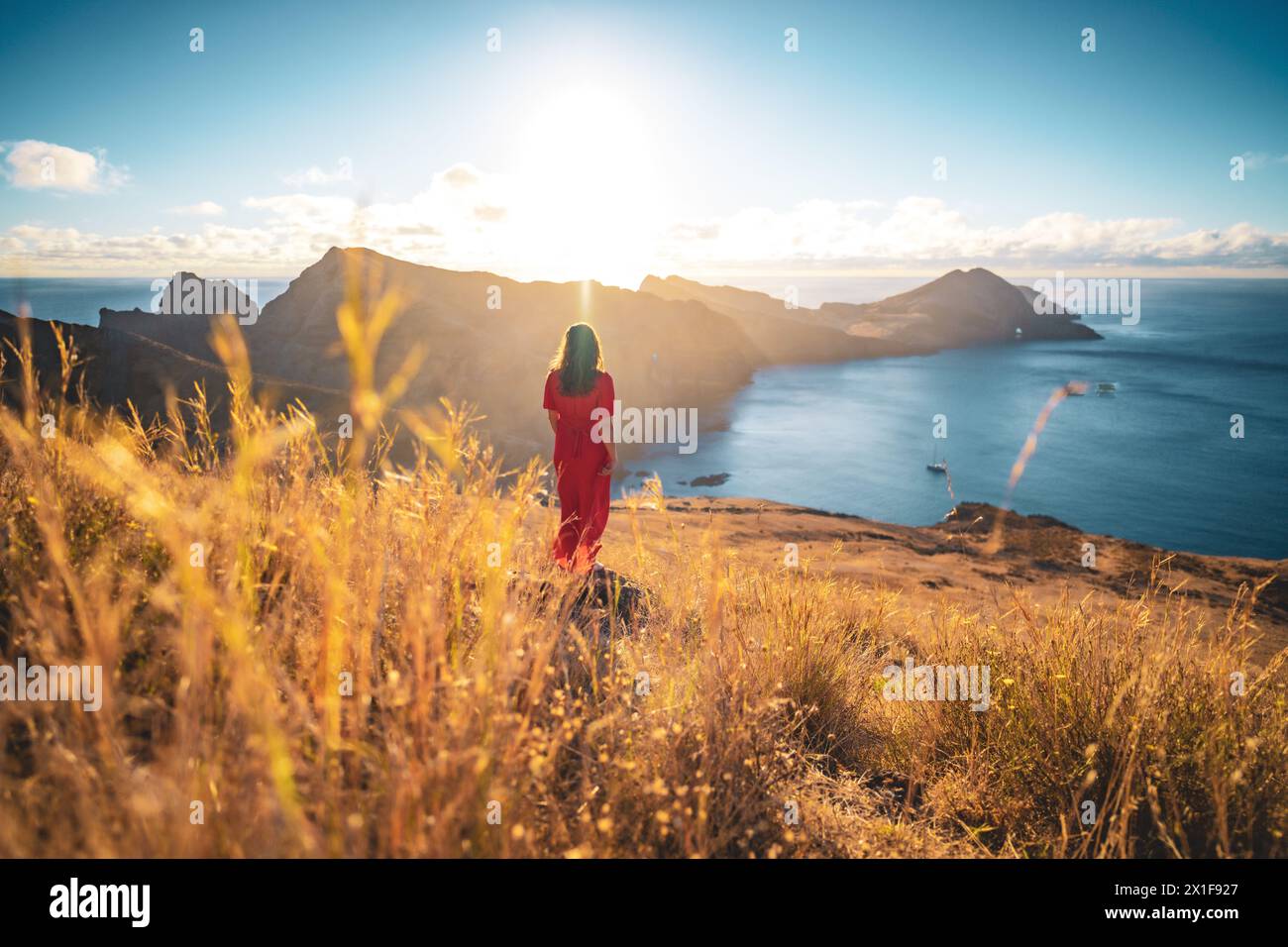 Description: Woman in red dress sunbathing with beautiful view on the ...